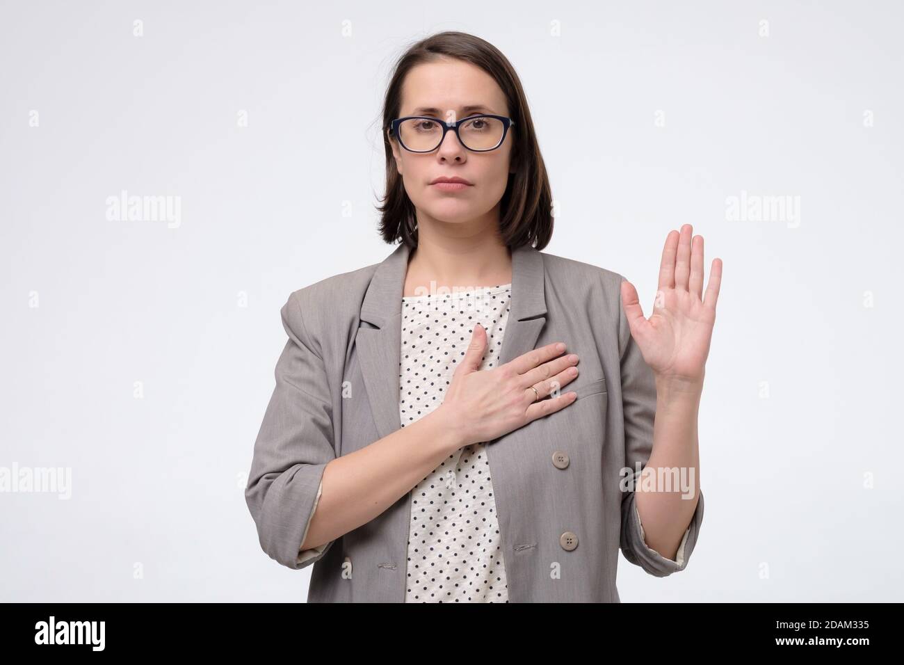 Woman swearing with hand on chest and open palm, making a loyalty ...