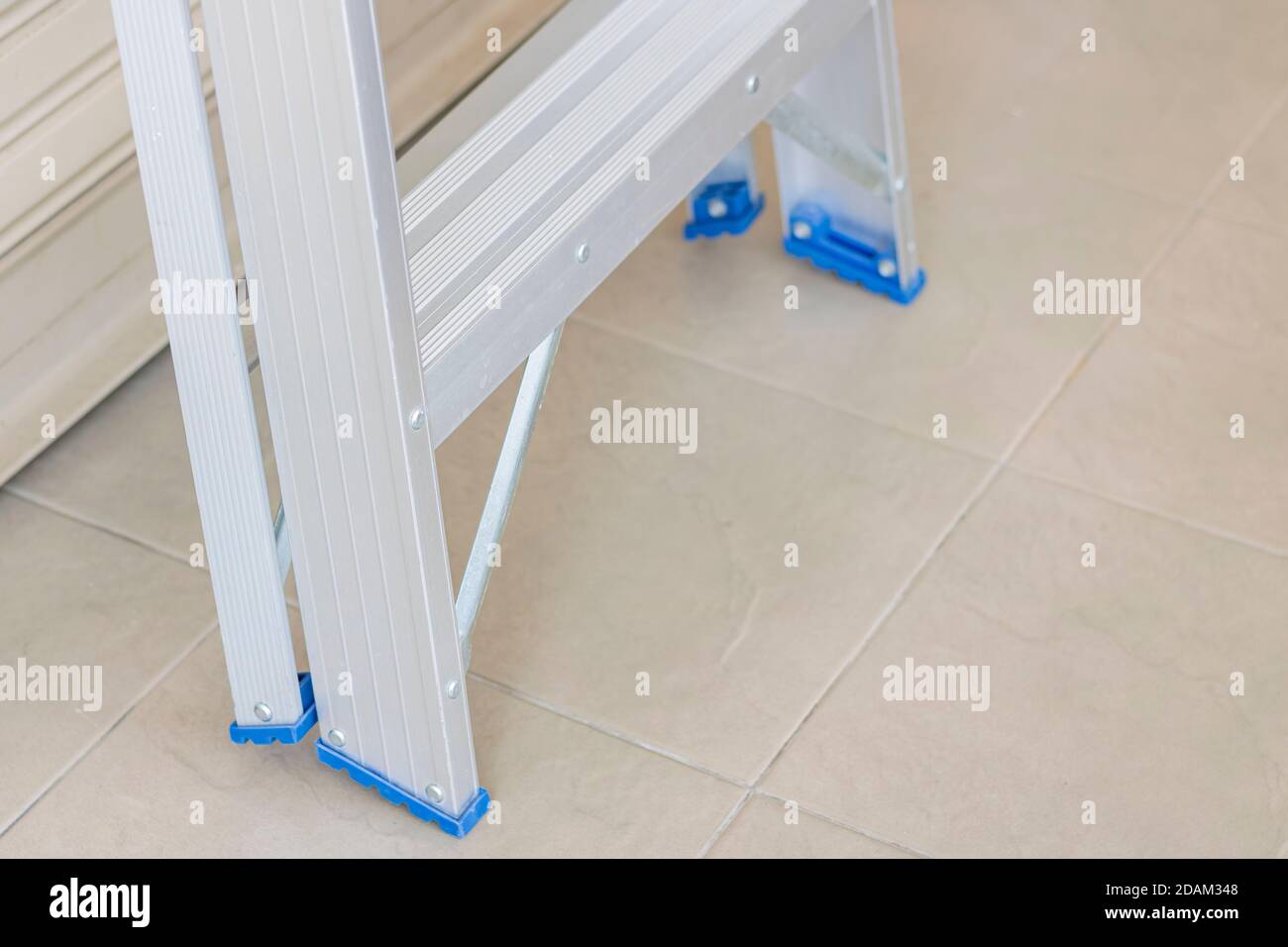 An aluminum foldable ladder leaning on the metal wall Stock Photo - Alamy