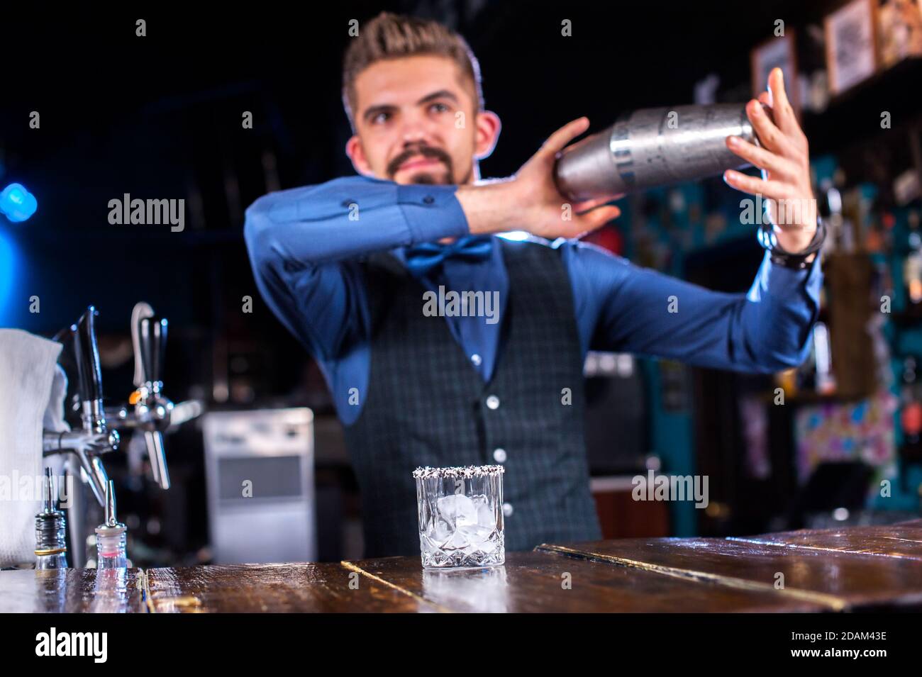 Expert barman makes a cocktail while standing near the bar counter in ...