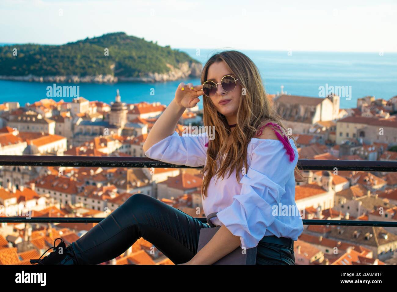 Attractive brunette influencer sitting on the city walls of Dubrovnik ...