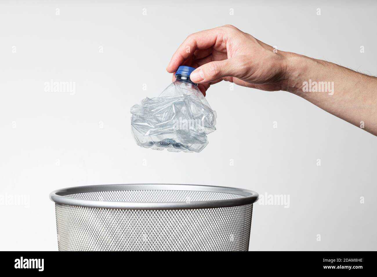 Hand throwing smashed empty plastic bottle into a trash can Stock Photo ...