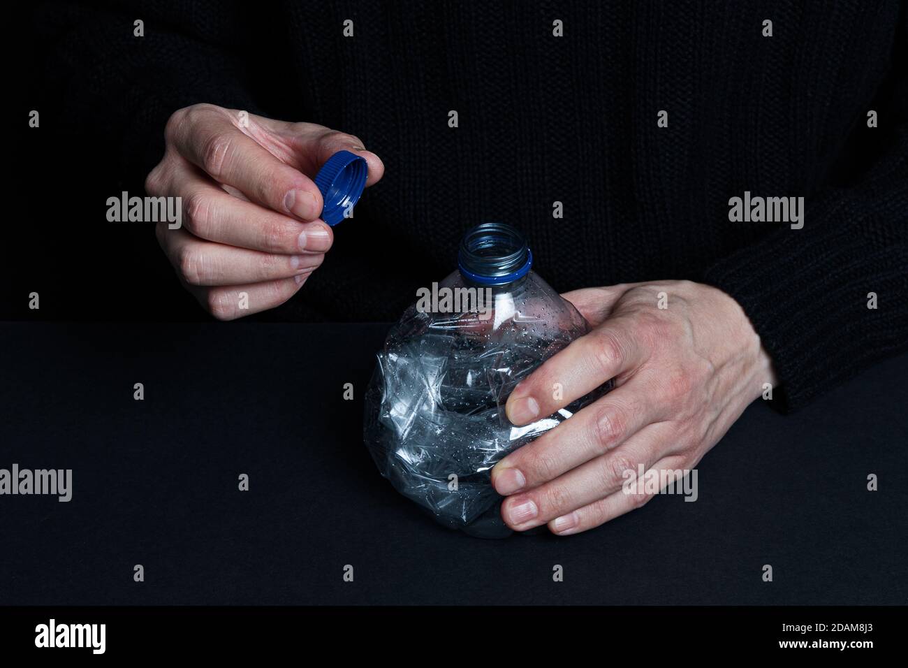 Man smashing a plastic bottle with his hands on black background Stock ...