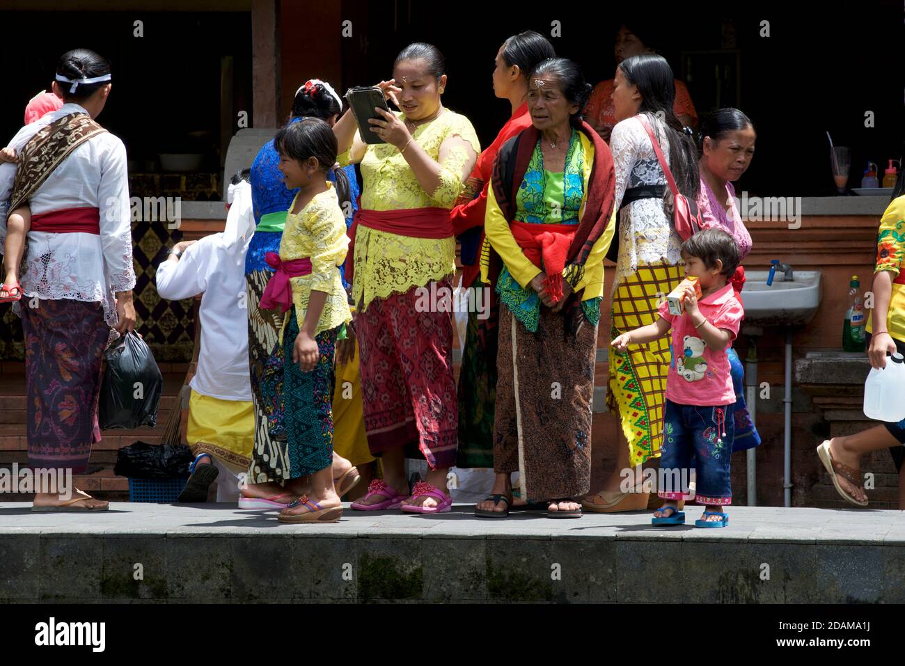 Balinese family in traditional Bainese attire sitting around a pool at ...