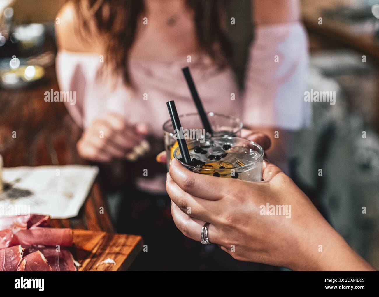 Shot of two people's hands toasting with alcohol glasses in the bar ...