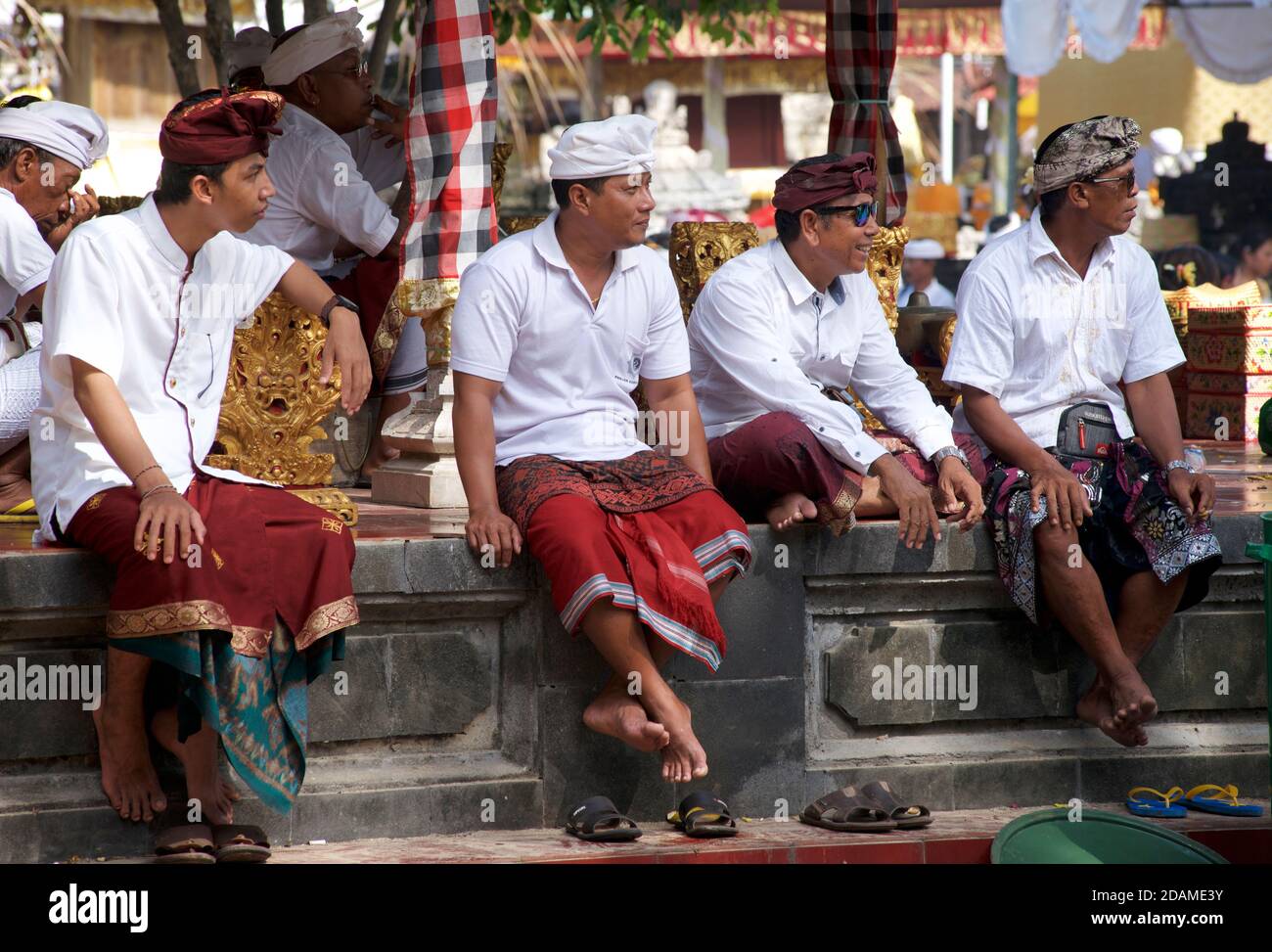 Balinese men in traditional festive attire relaxing at Sakenan temple ...
