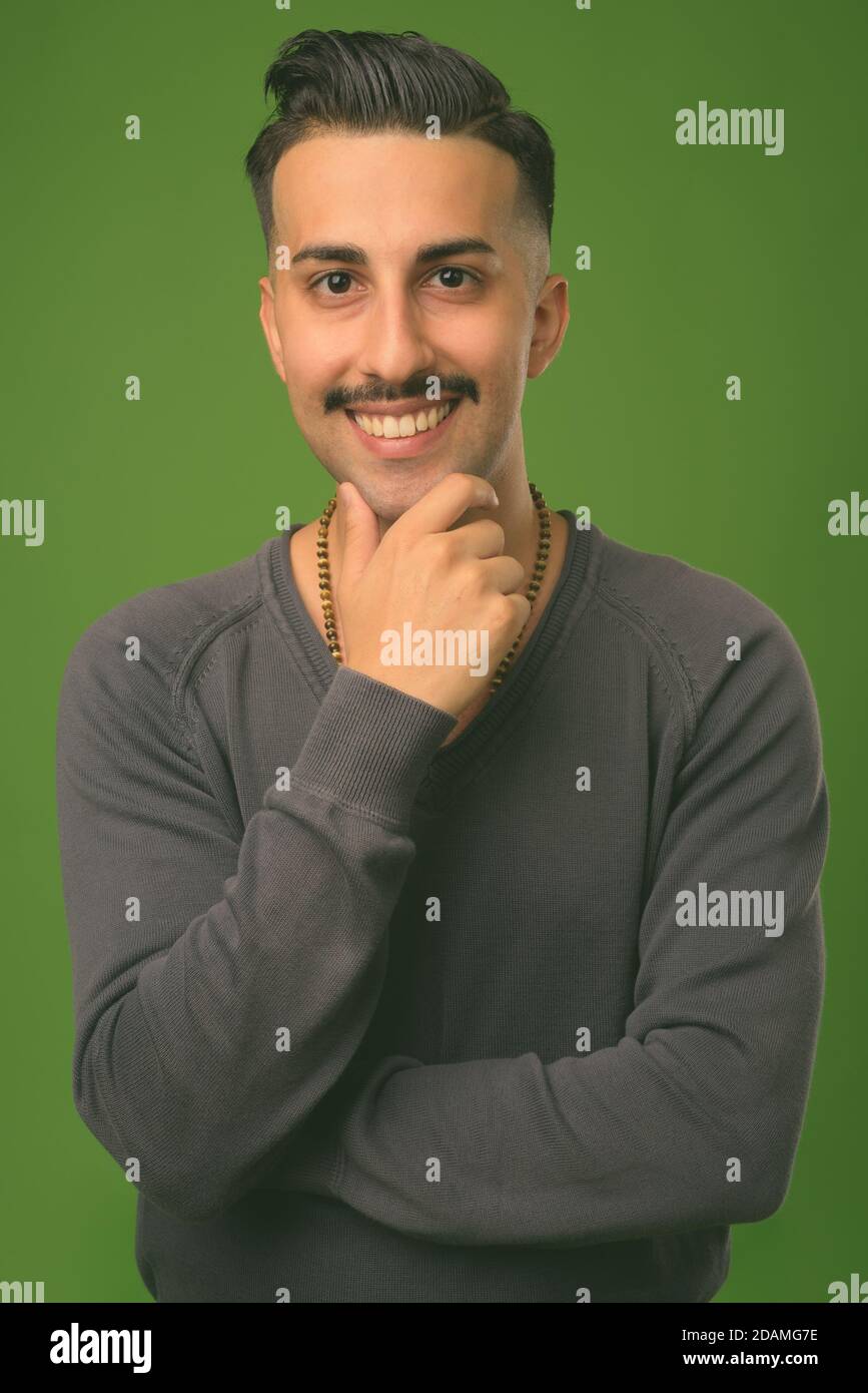 Young handsome Iranian man with mustache against green background Stock ...