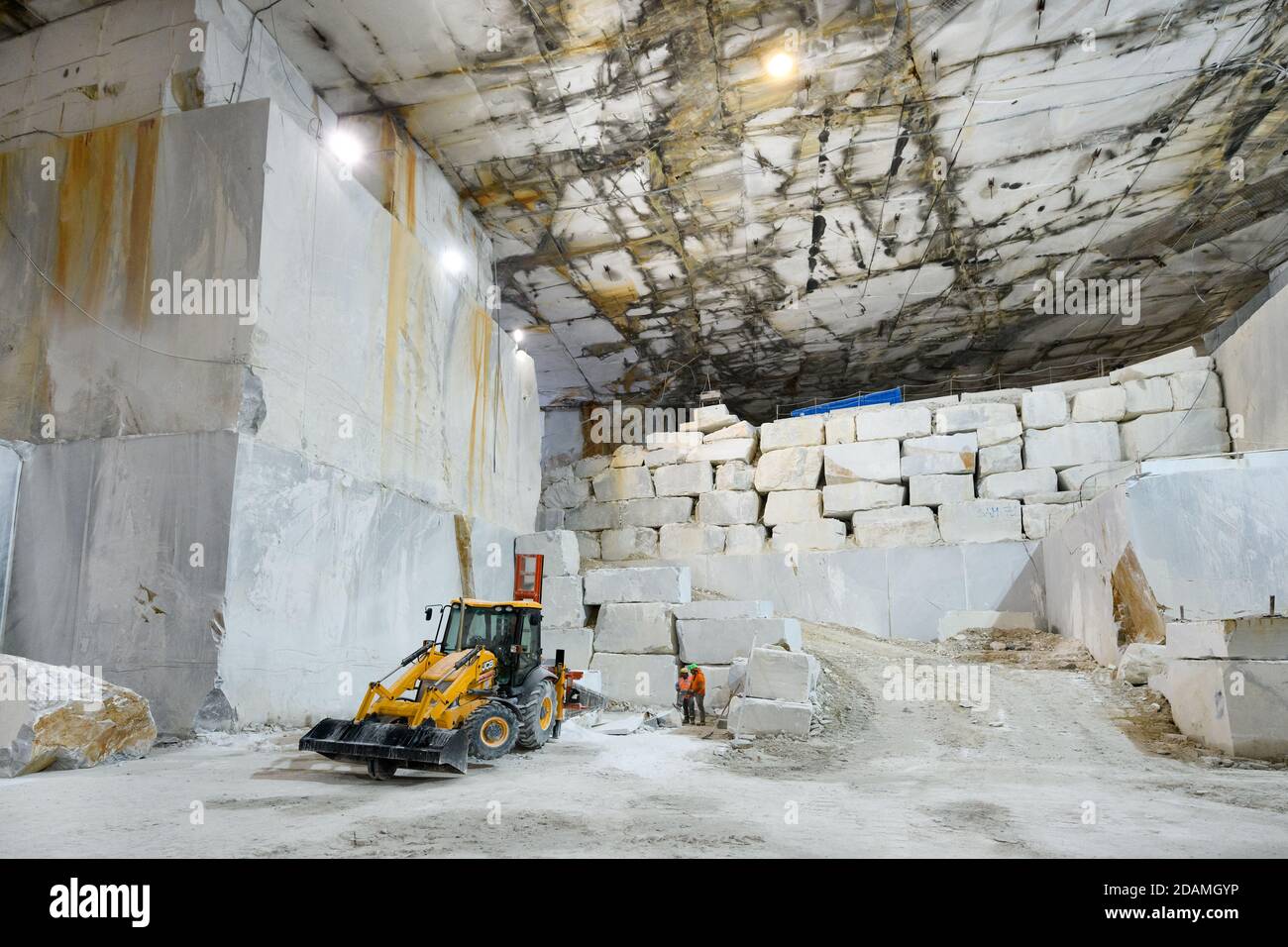 Workers and machinery inside a marble quarry or open cast mine during ...