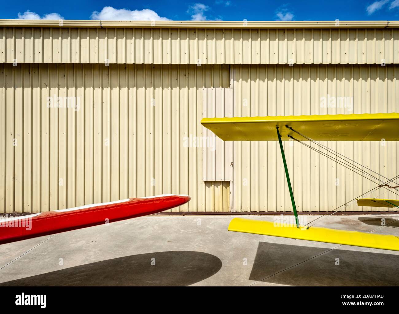 a red wing and a yellow biplane wings against a faded yellow corrugated ...