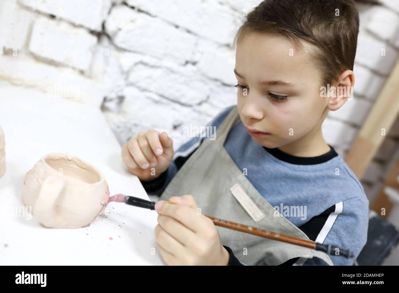 Boy painting clay pot in pottery workshop Stock Photo - Alamy