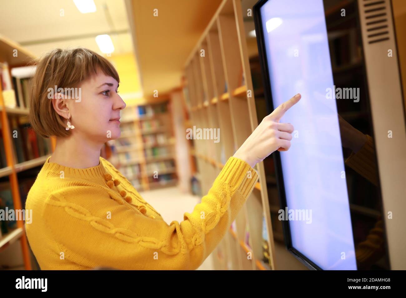 Woman choosing book using touchscreen in library Stock Photo - Alamy