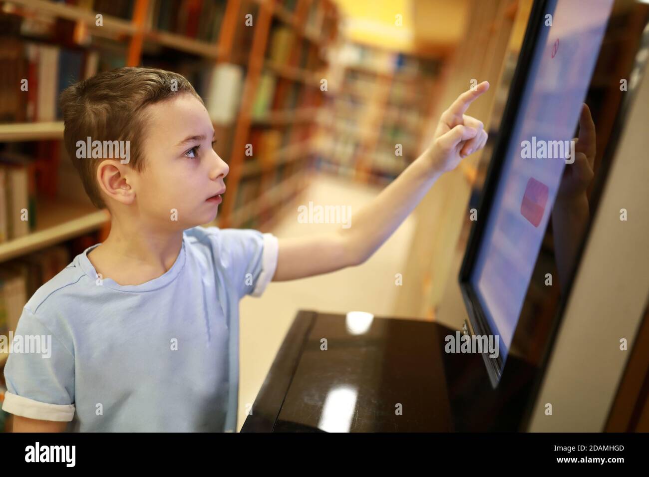 Child choosing book using touchscreen in library Stock Photo - Alamy