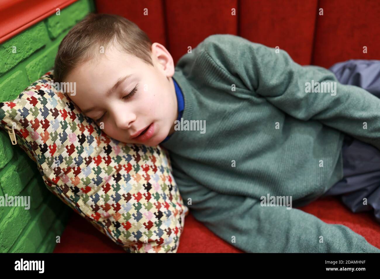 Tired boy sleeping on sofa in cafe Stock Photo - Alamy