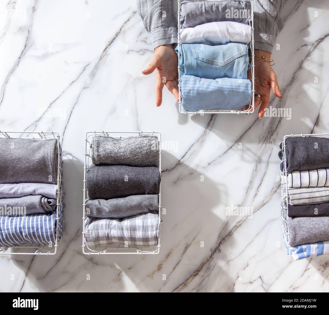 Neatly folded clothes and pyjamas in the metal mesh organizer basket on ...