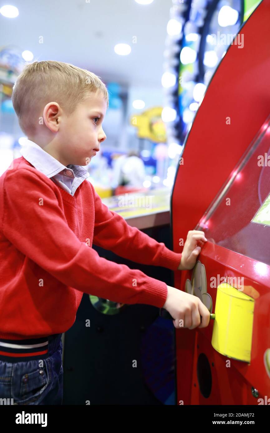 KId playing arcade game in amusement park Stock Photo - Alamy