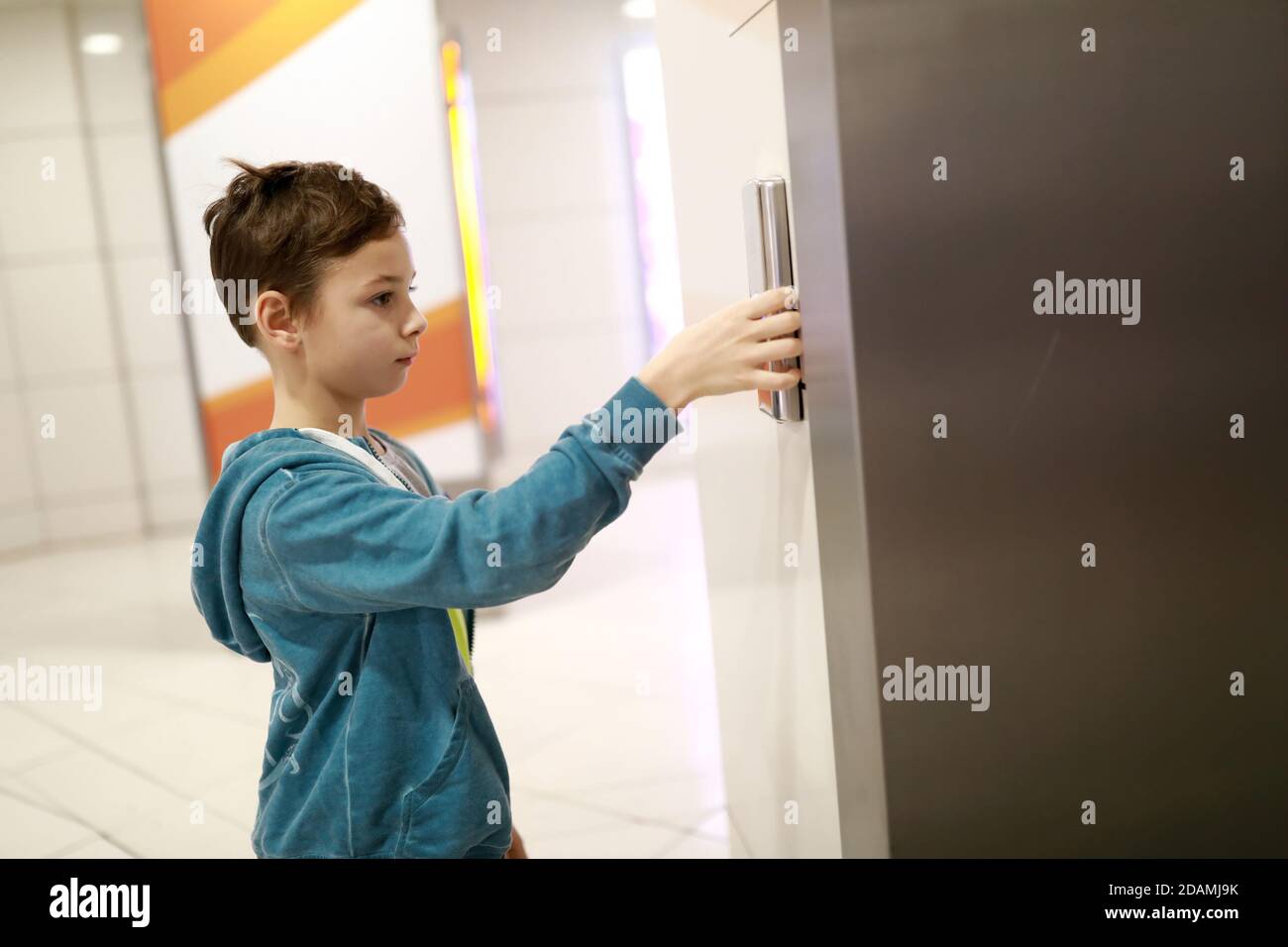 Boy calls elevator in a shopping center Stock Photo - Alamy