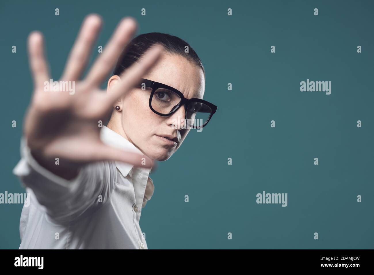Confident woman putting her hand forward and making a stop gesture ...