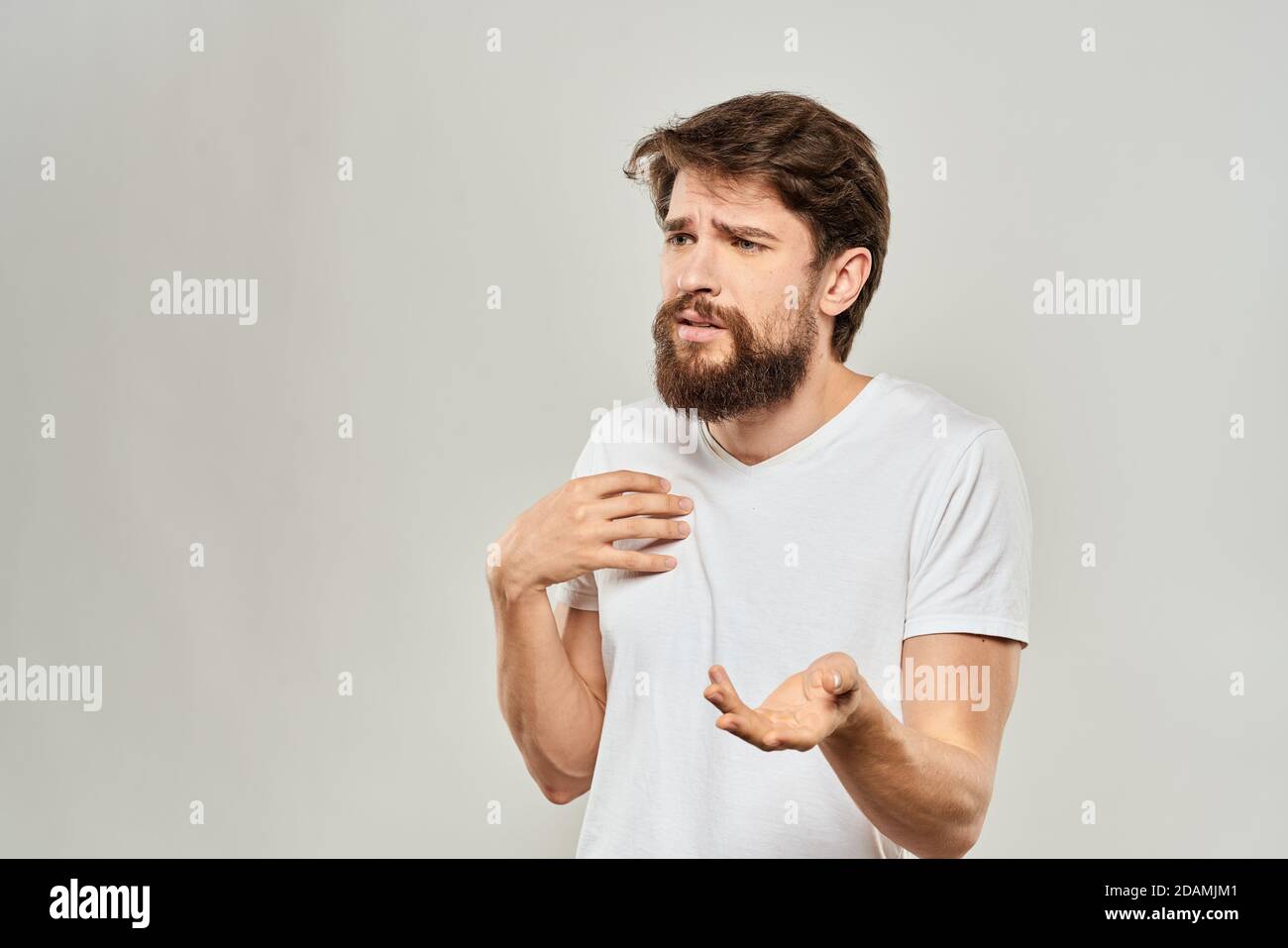 A man in a white t-shirt with a beard emotions displeased facial ...