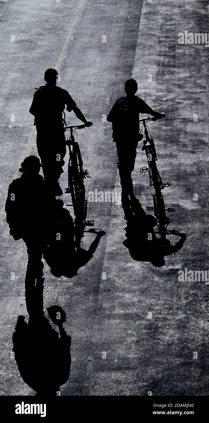 Pedestrian shadows on a blacktop road. A shadow is a dark (real image ...