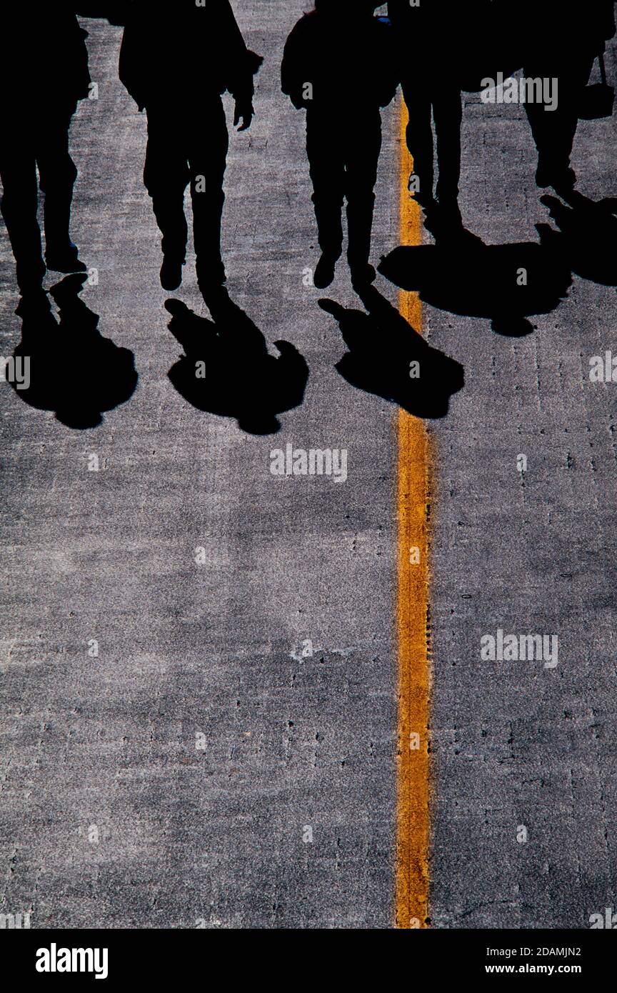 Pedestrian shadows on a blacktop road. A shadow is a dark (real image ...