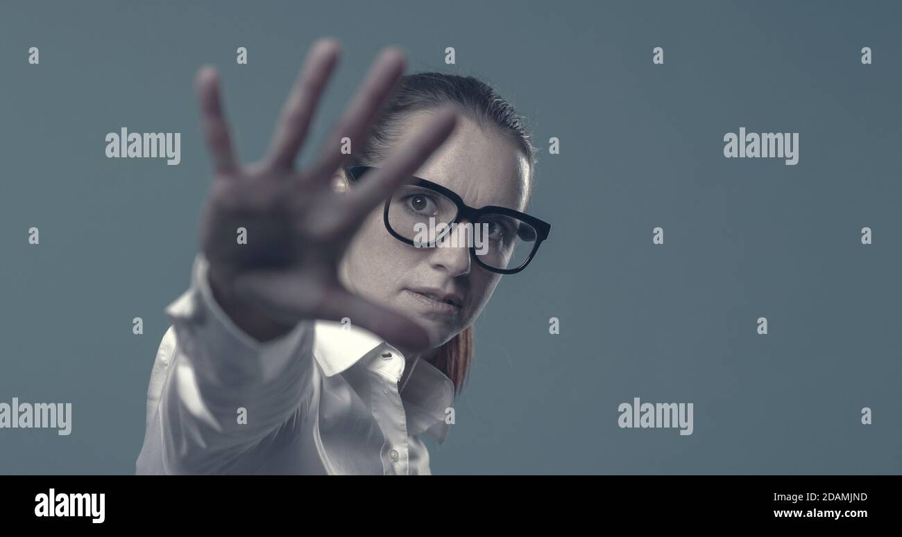 Confident woman putting her hand forward and making a stop gesture ...