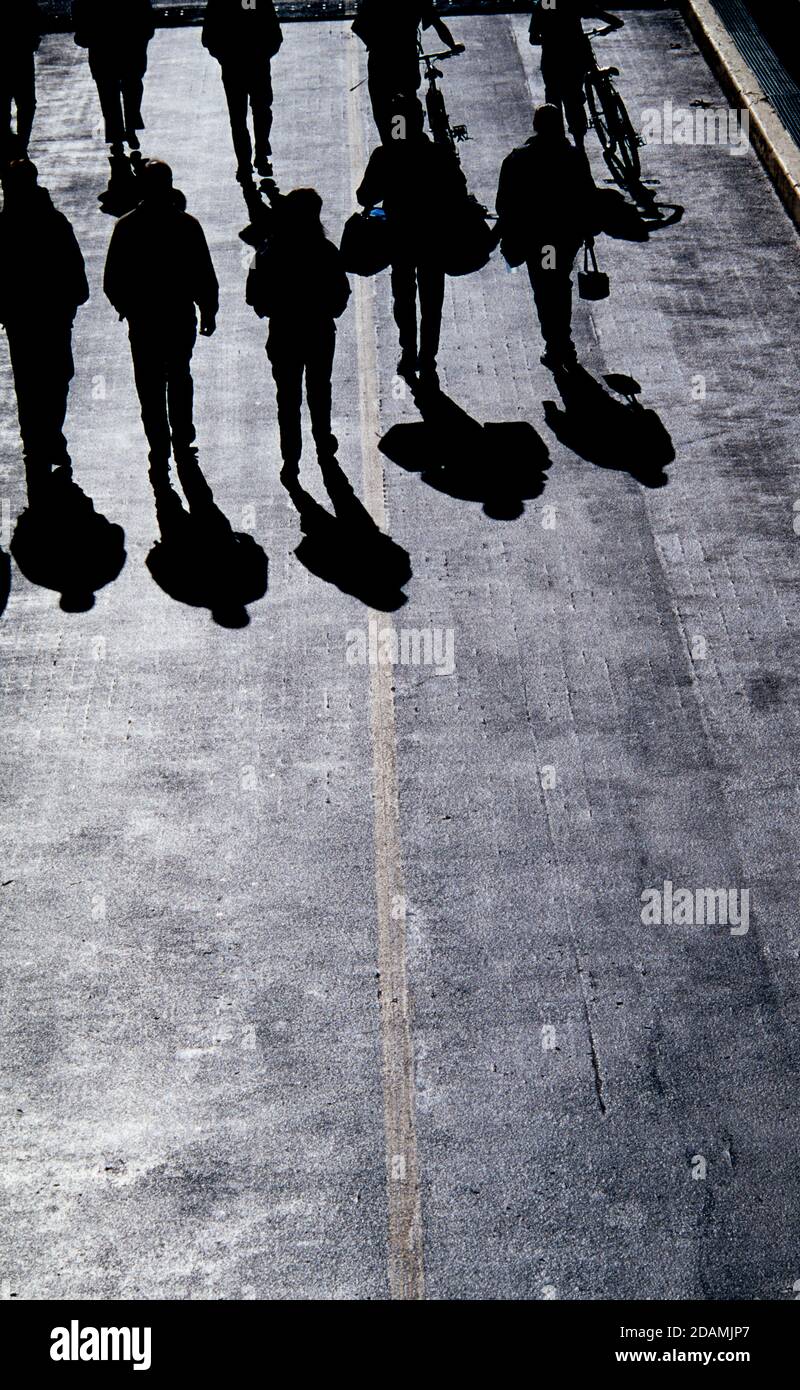 Pedestrian shadows on a blacktop road. A shadow is a dark (real image ...