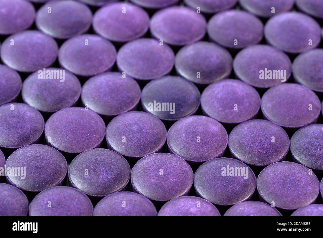 close-up background of many purple organic powder tablets laid tight in ...