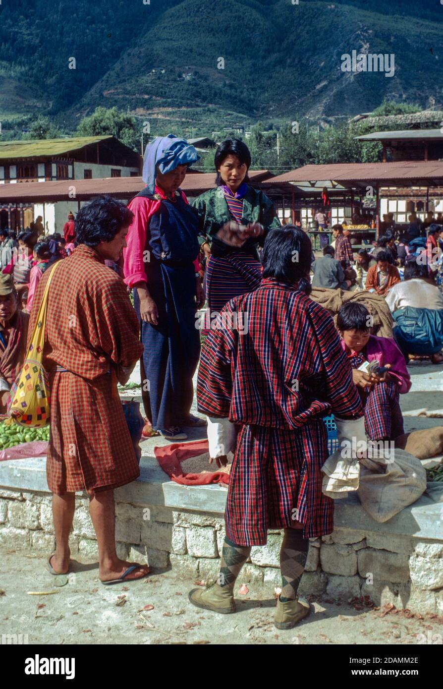 Men and women wear traditional dress in the market at Thimphu, Bhutan ...