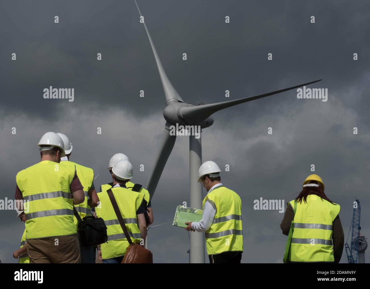 workers wearing security vests at the construction site of wind power ...