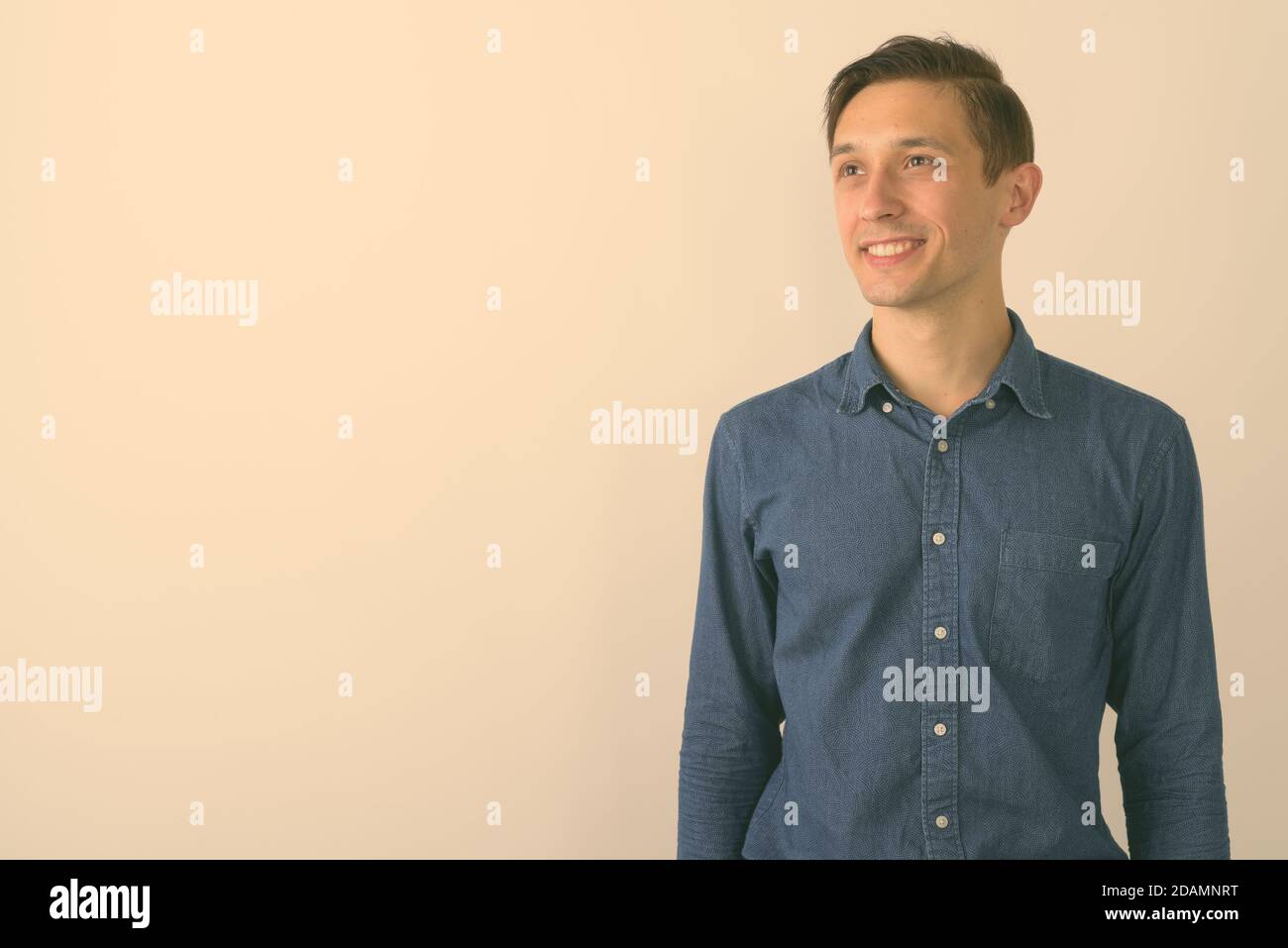 Studio shot of happy young handsome man smiling and thinking while ...