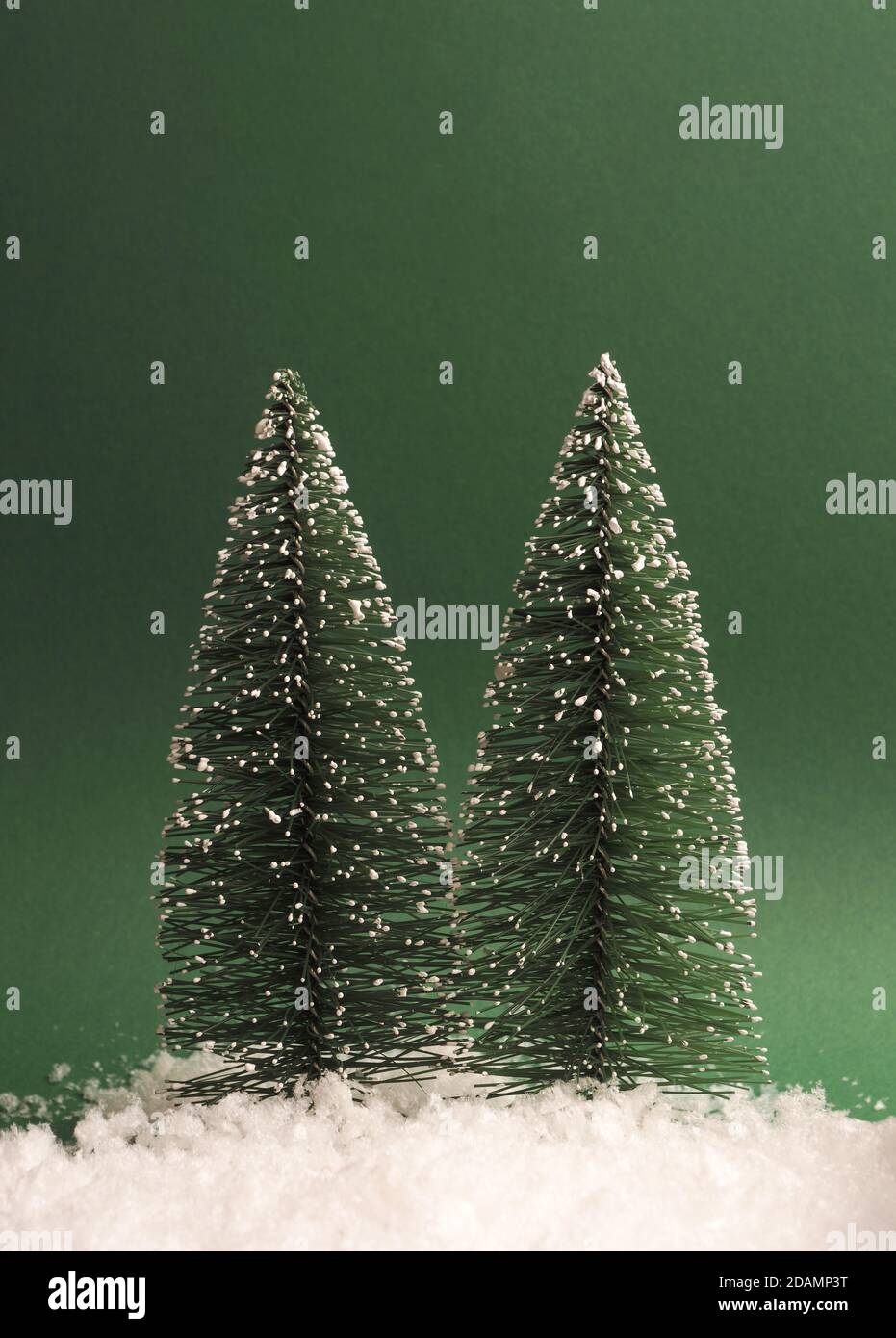 Two fir trees with snow on a green paper background, space for text on ...