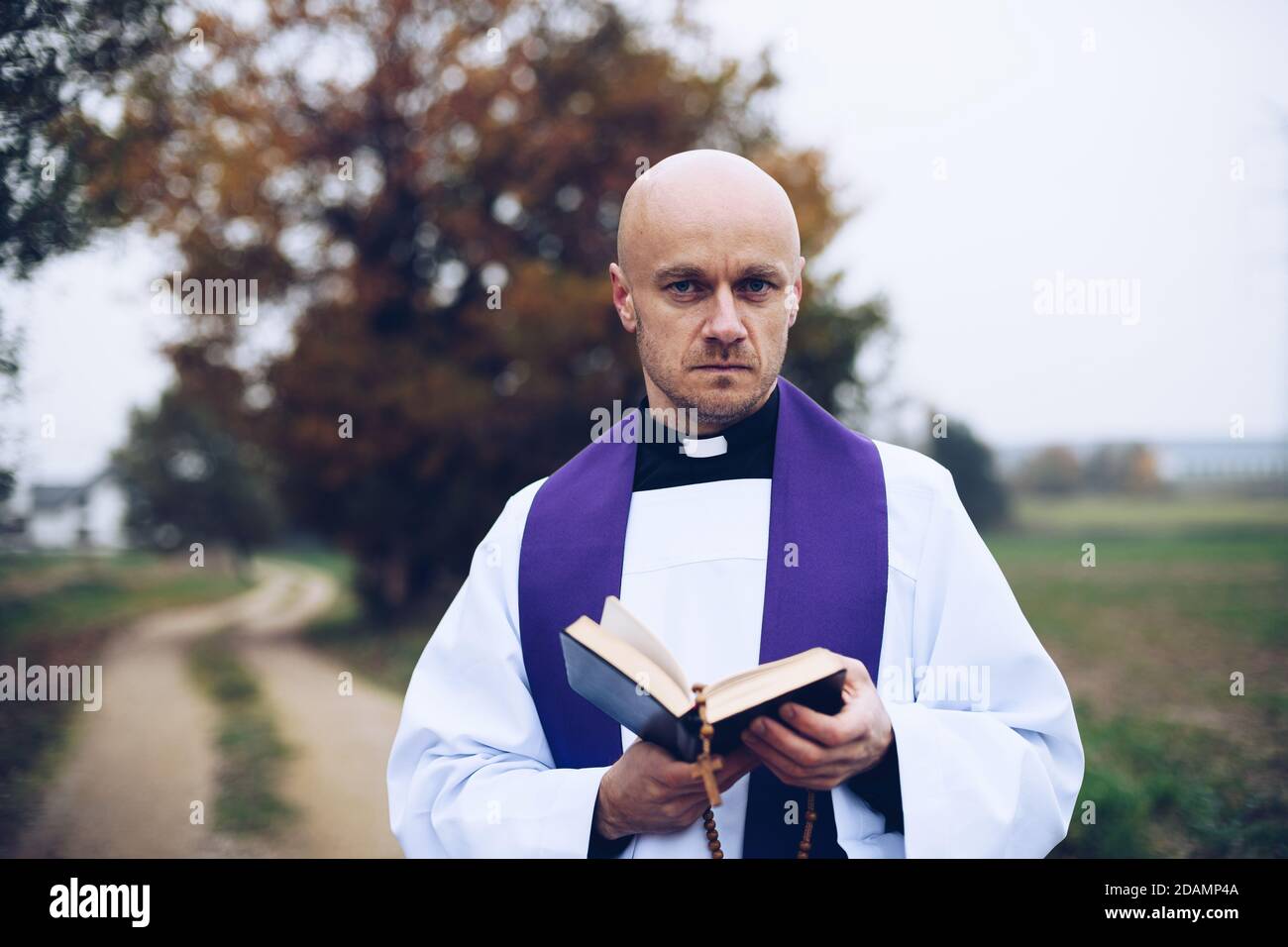 Catholic priest reading bible on a country road Stock Photo - Alamy
