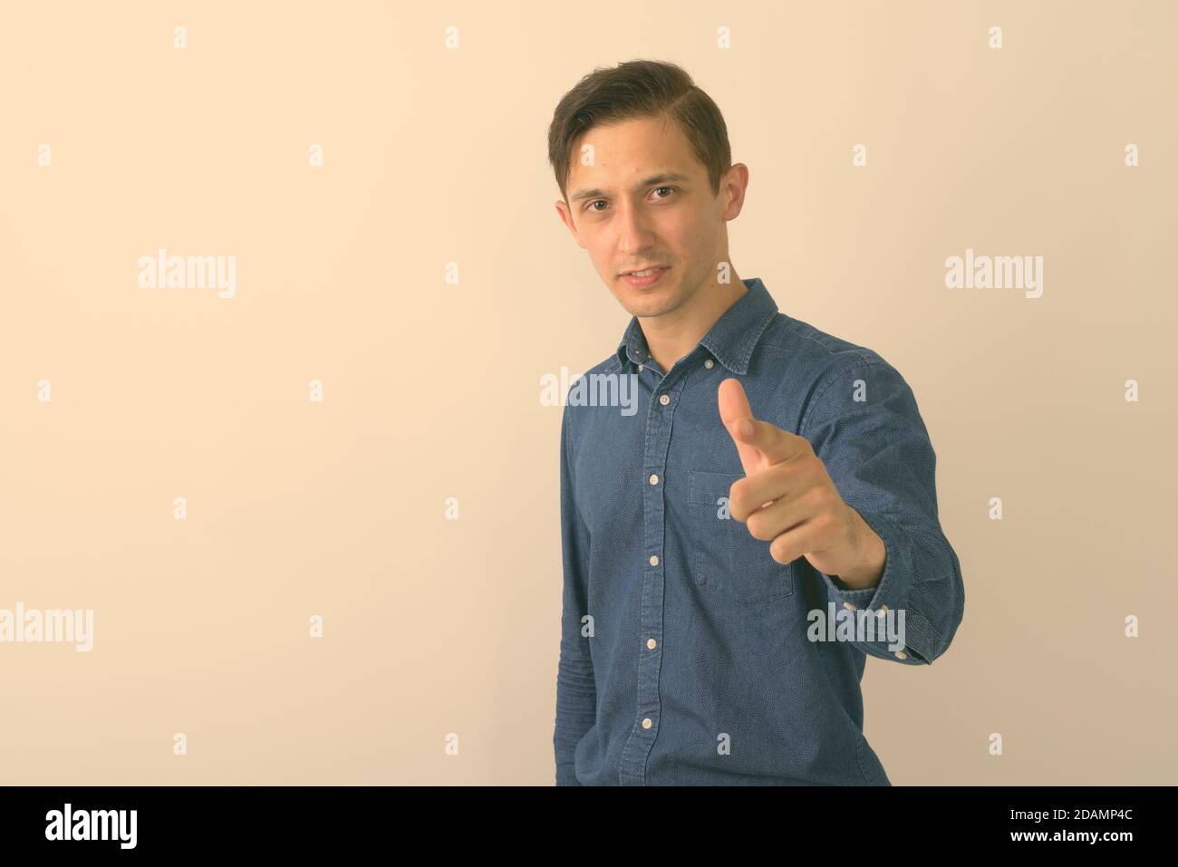 Studio shot of young handsome man pointing at camera against white ...