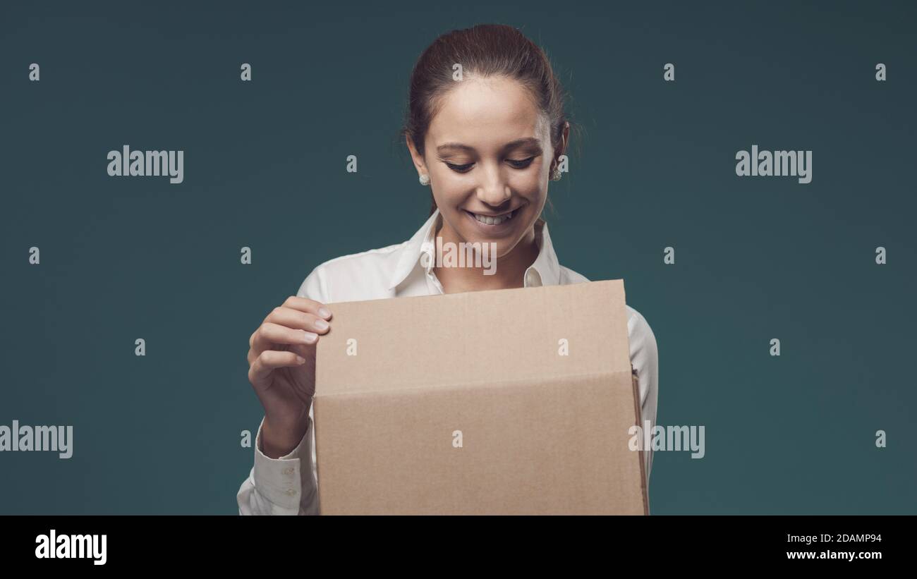 Happy woman opening a delivery box, she is happy with the product she ...