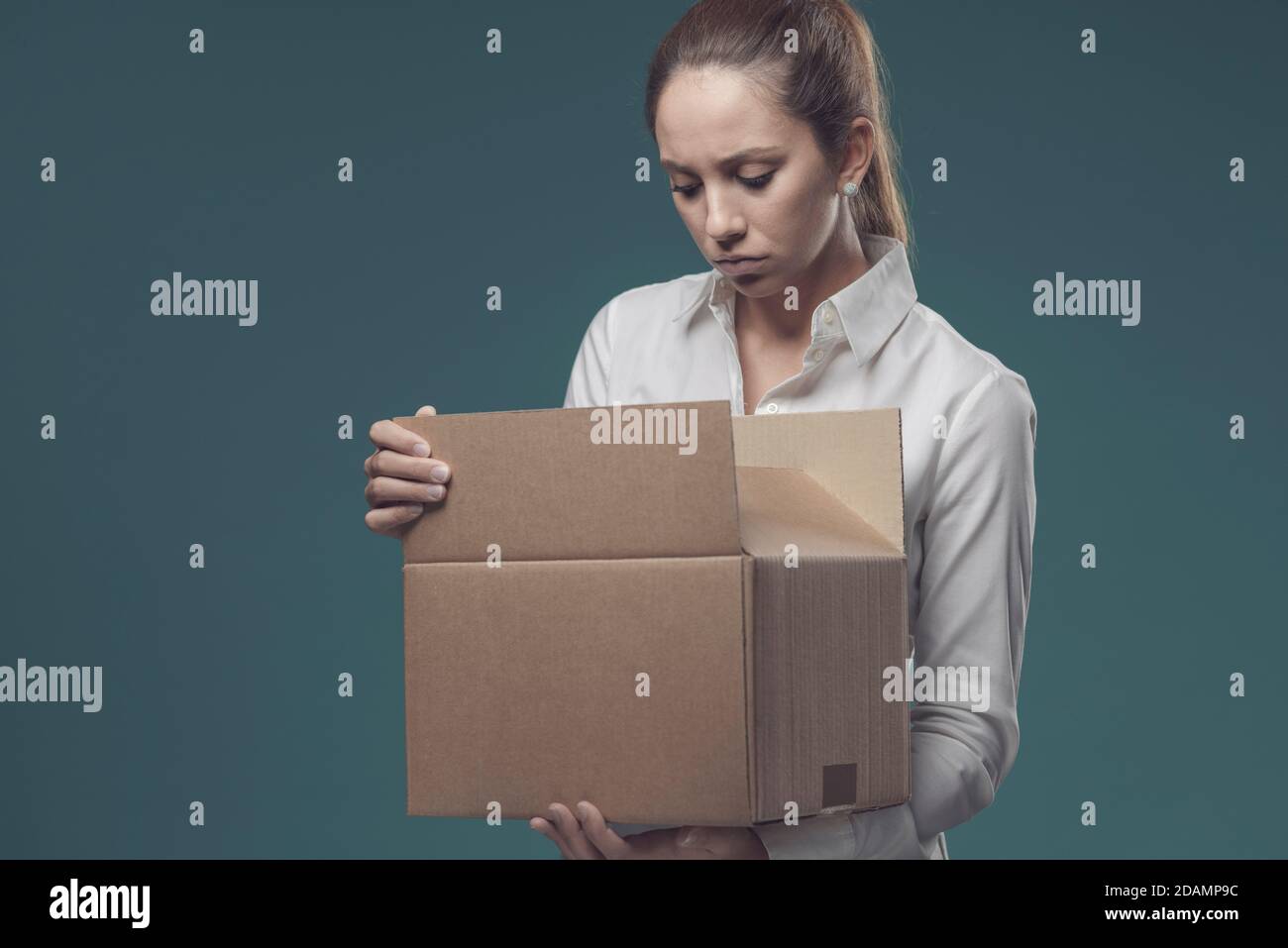 Disappointed woman looking into a cardboard box, she has received the ...
