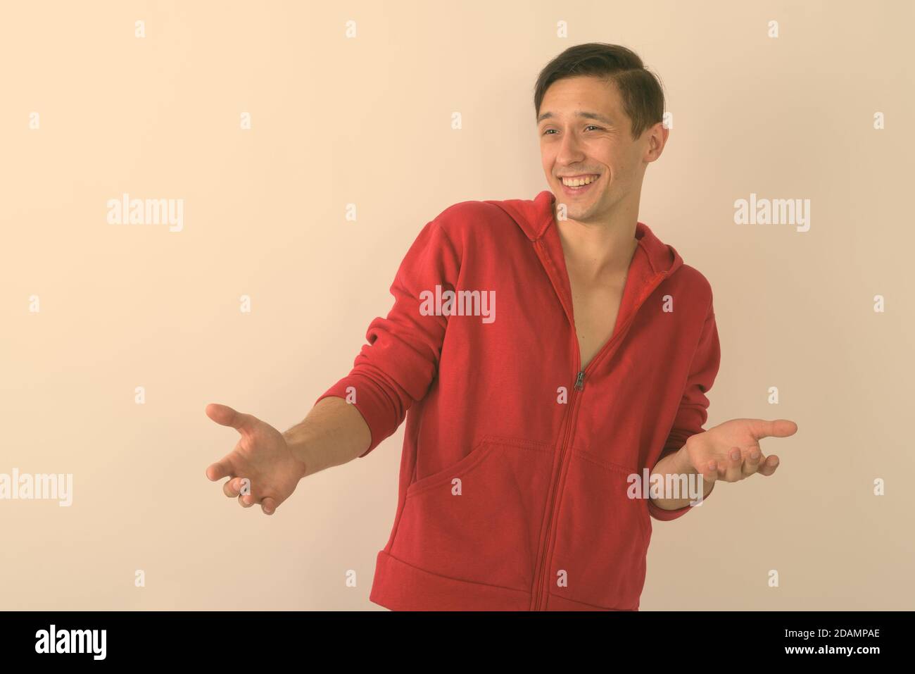 Studio shot of happy young handsome man smiling while looking confused ...