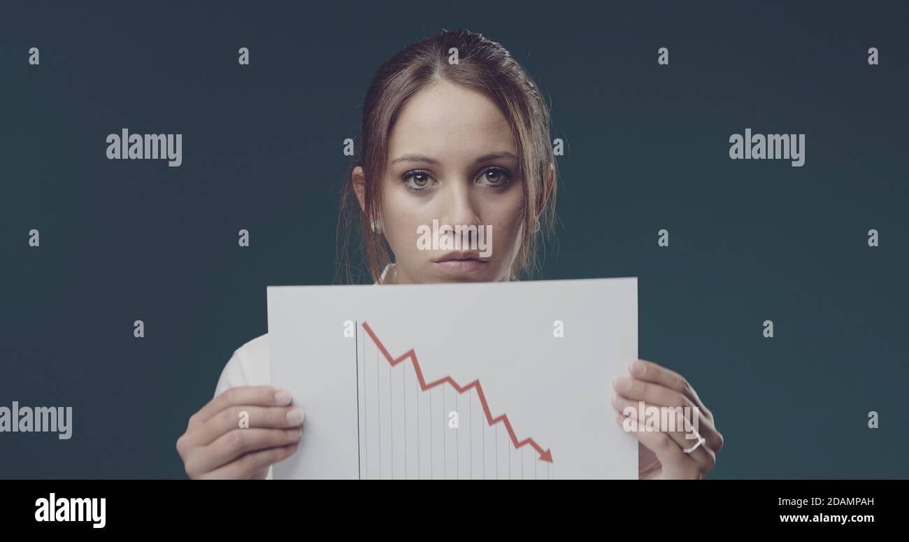 Disappointed businesswoman holding a negative financial chart ...