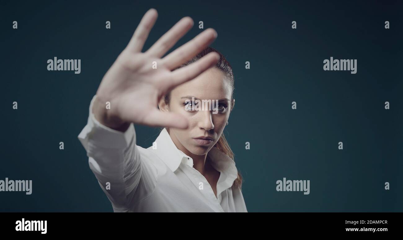 Young confident woman putting her hand forward and doing a stop gesture ...