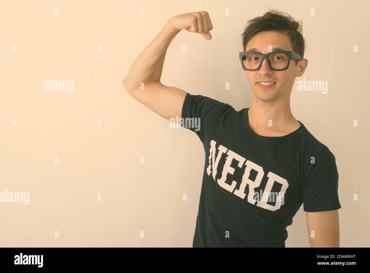 Studio shot of young happy nerd man smiling while flexing arm and ...