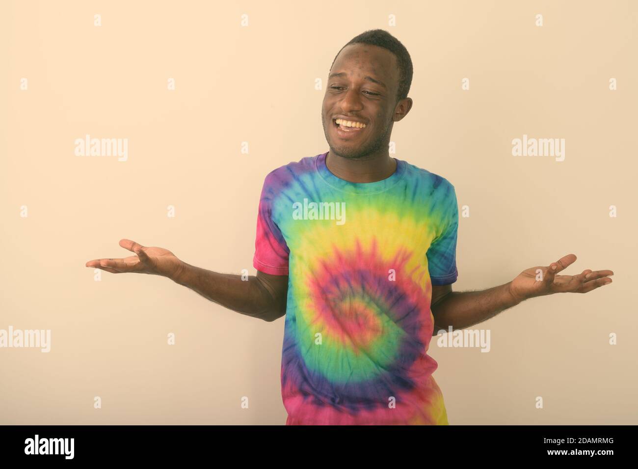 Studio shot of young happy black African man shrugging shoulders ...