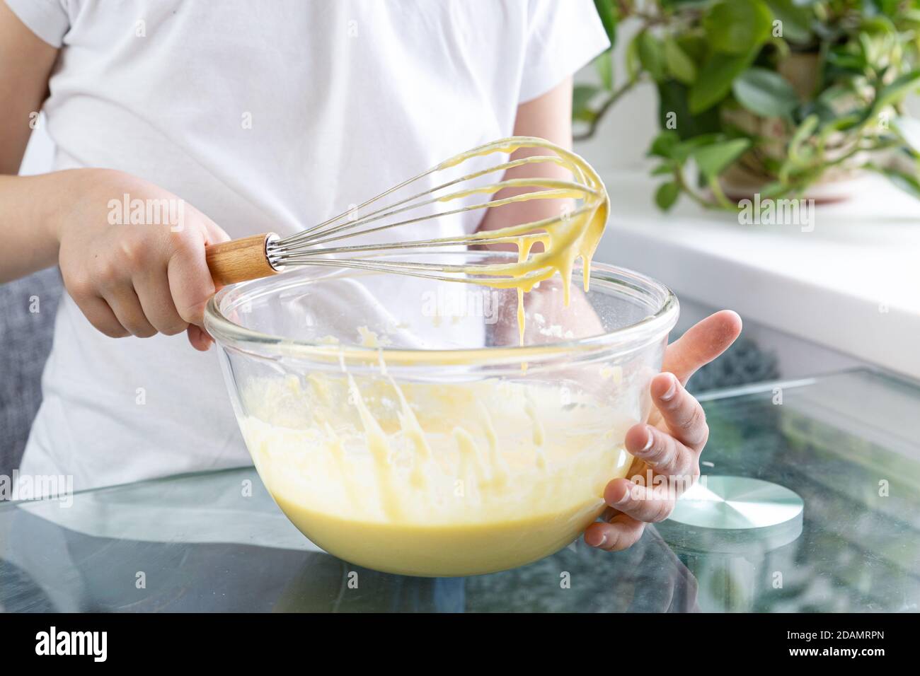 A close-up of the upper body of a child stirs the wafer dough by hand ...