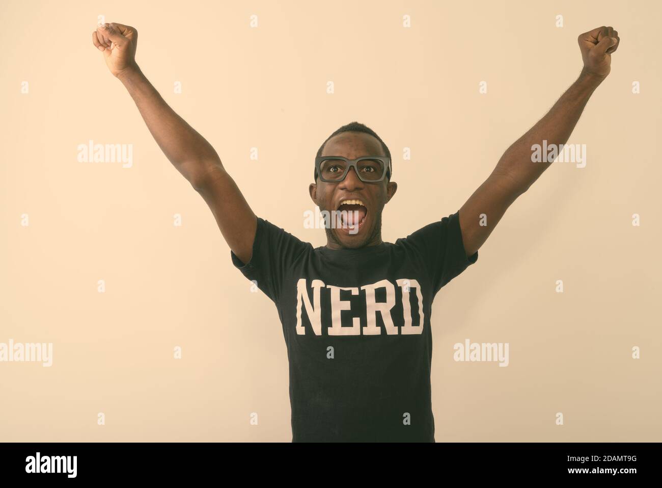 Studio shot of happy young black African geek man with both arms raised ...