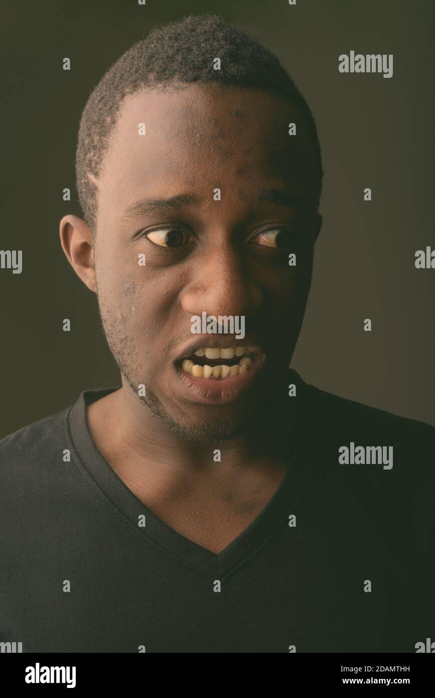 Studio shot of angry young black African man screaming in dark room ...