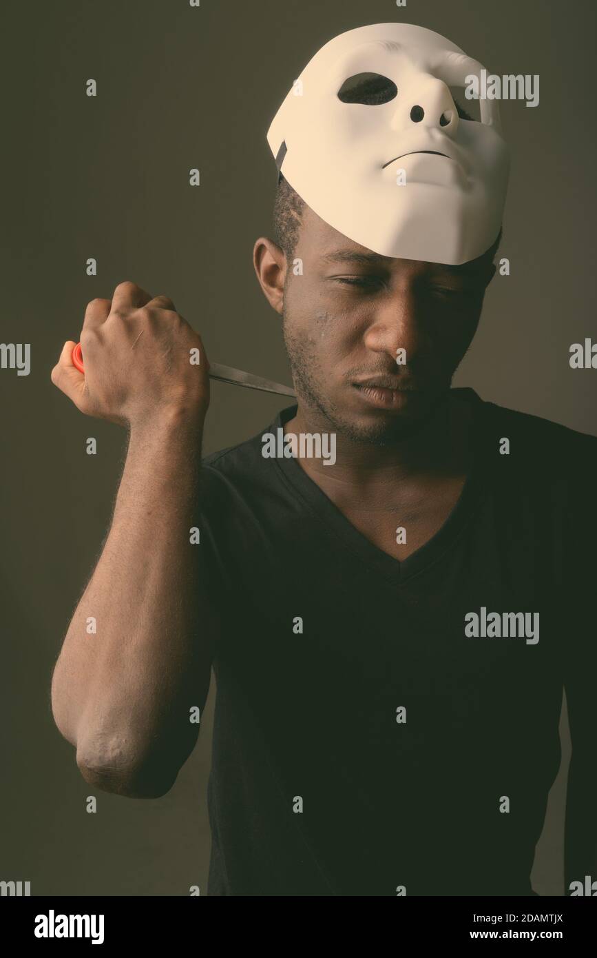 Studio shot of young black African man holding mask and pressing ...