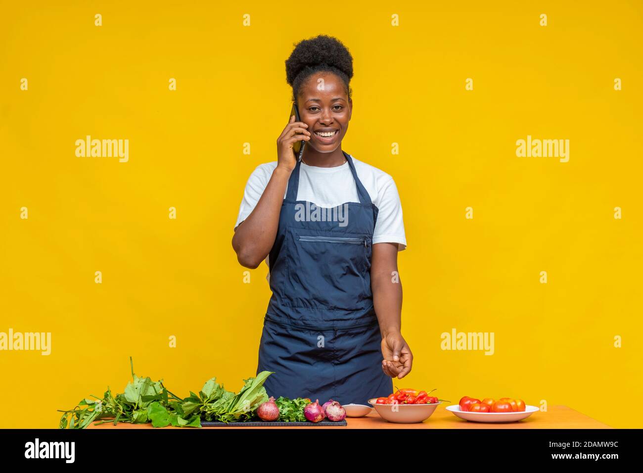 african female chef making a phone call, with food ingredients on a ...