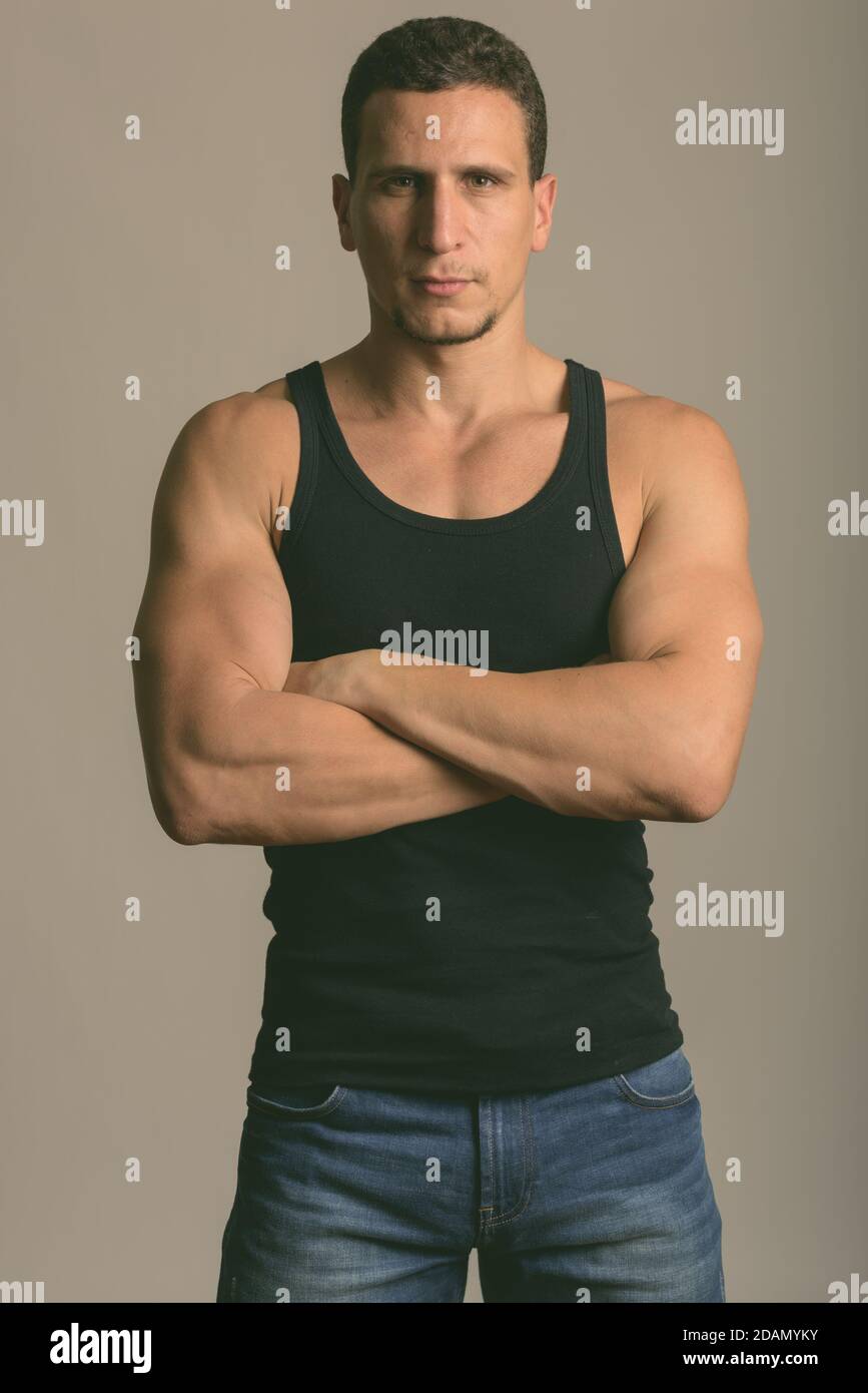 Studio shot of young muscular Persian man standing with arms crossed ...
