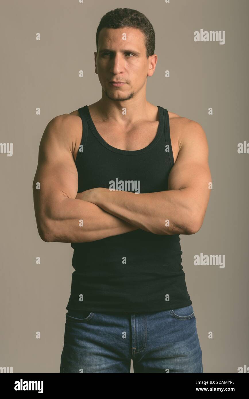 Studio shot of young muscular Persian man thinking with arms crossed ...
