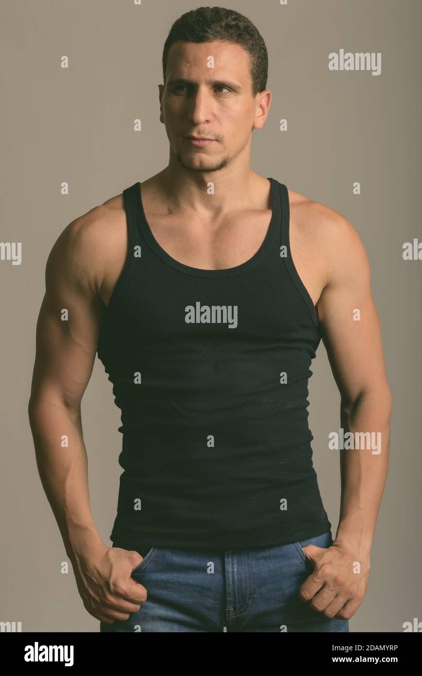 Studio shot of young muscular Persian man standing and thinking against ...