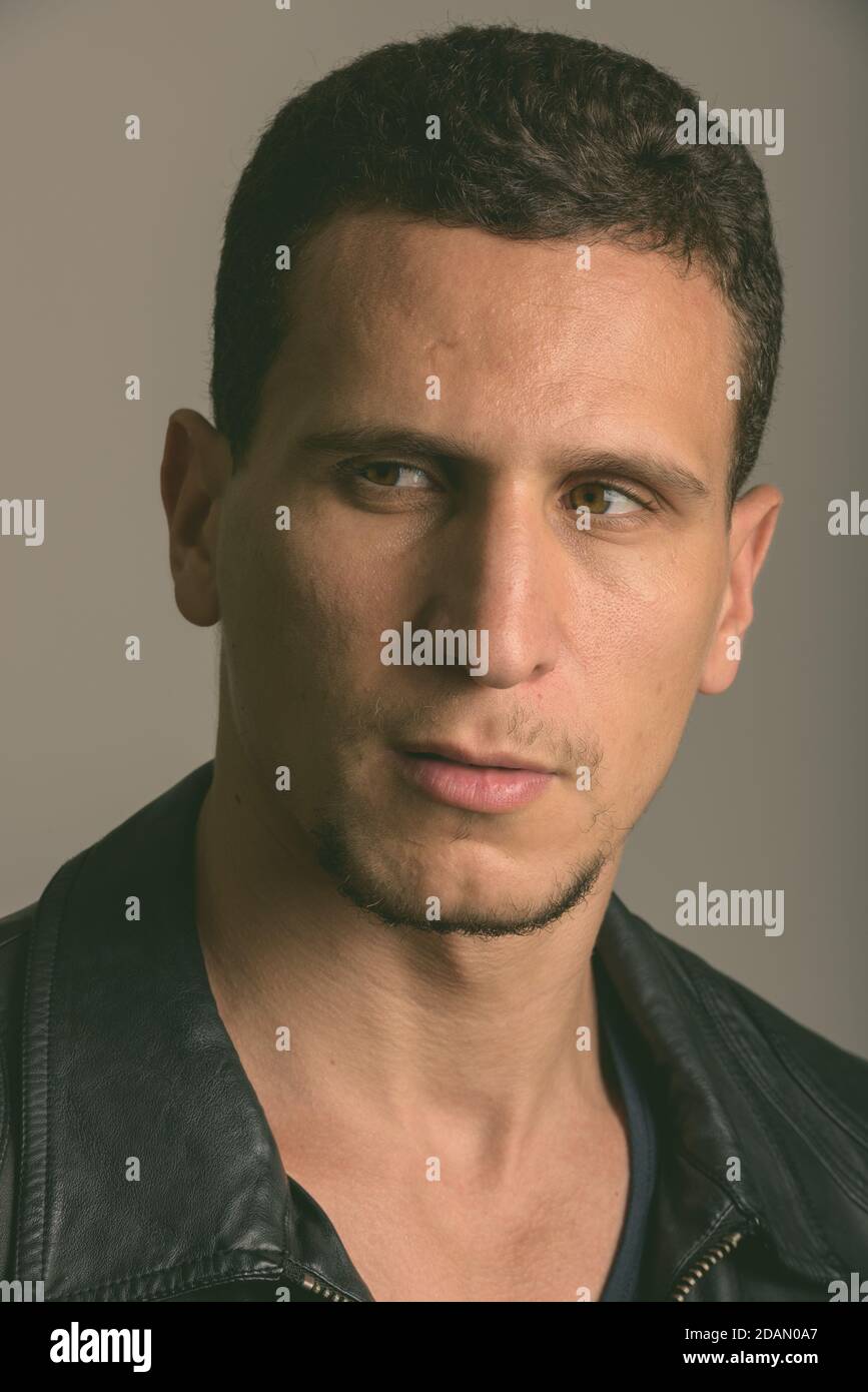 Face of young muscular Persian man thinking while looking suspicious ...