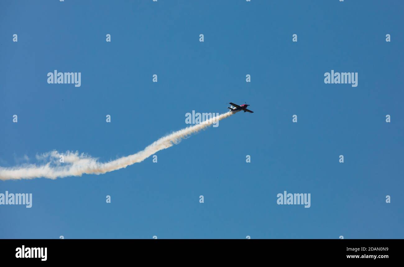 Silhouette of an airplane with a trace of smoke behind performing ...