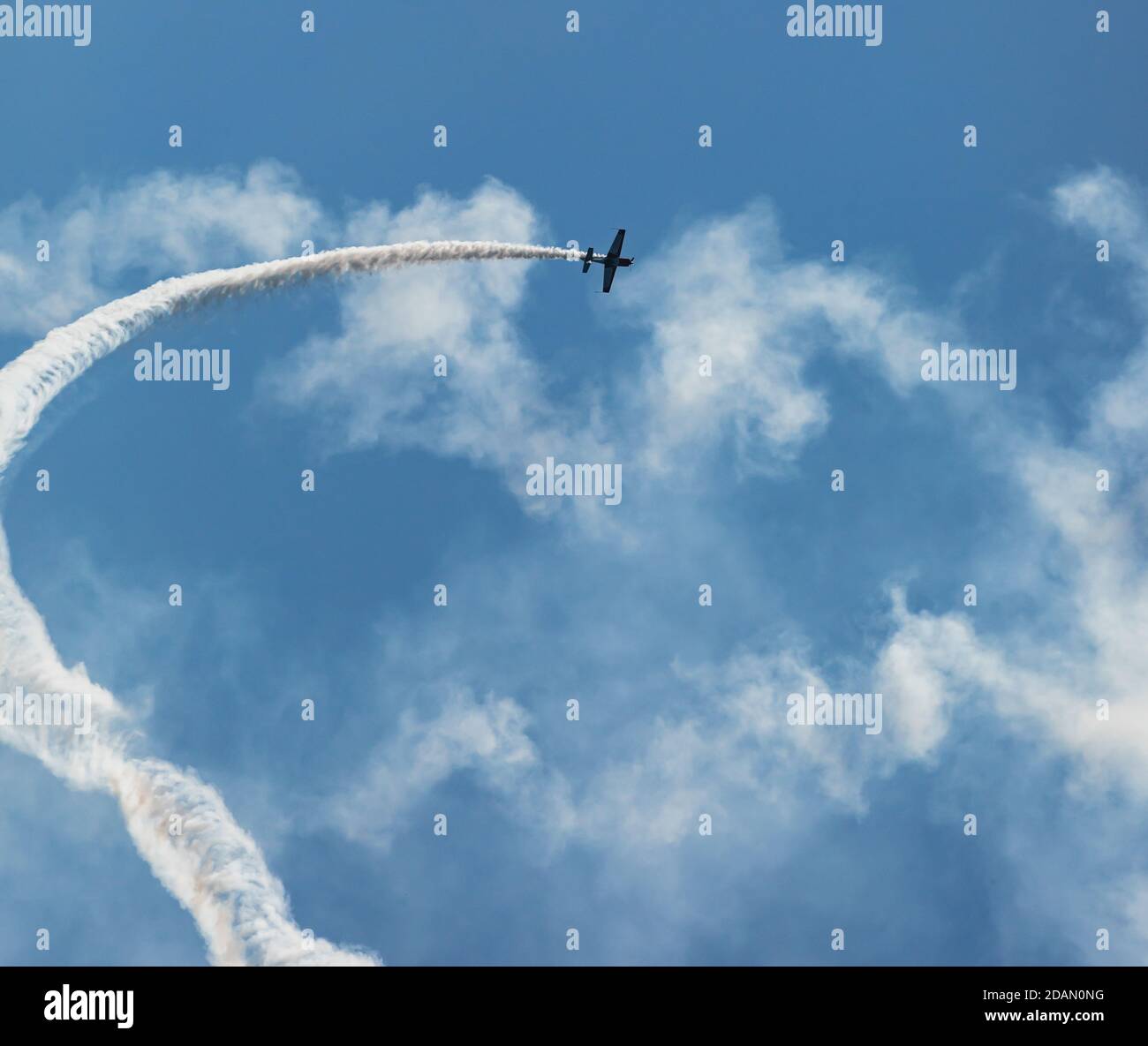 Silhouette of an airplane with a trace of smoke behind performing ...